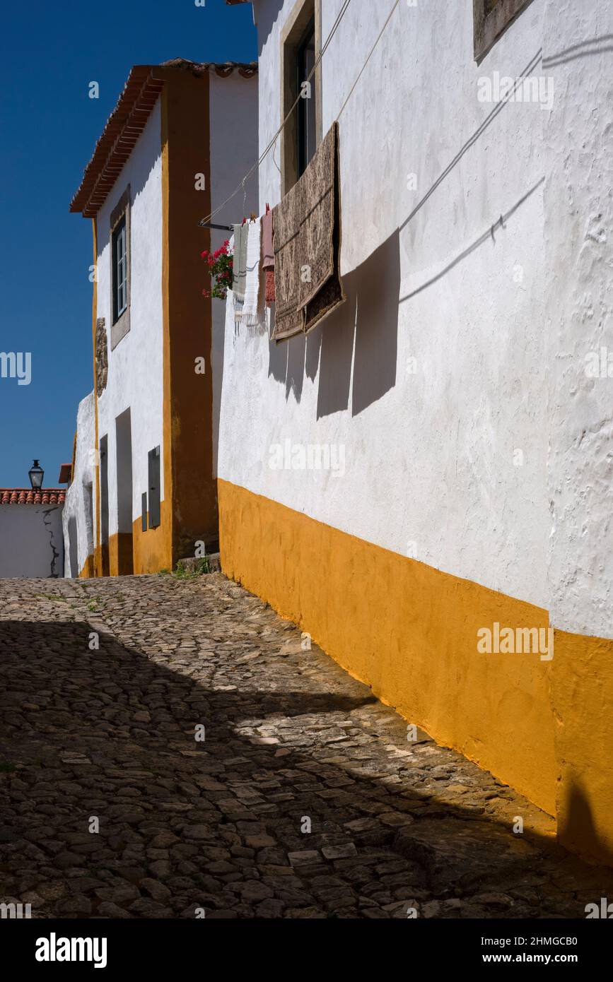 Bright yellow plinth brightens traditional stepped street in Óbidos ...