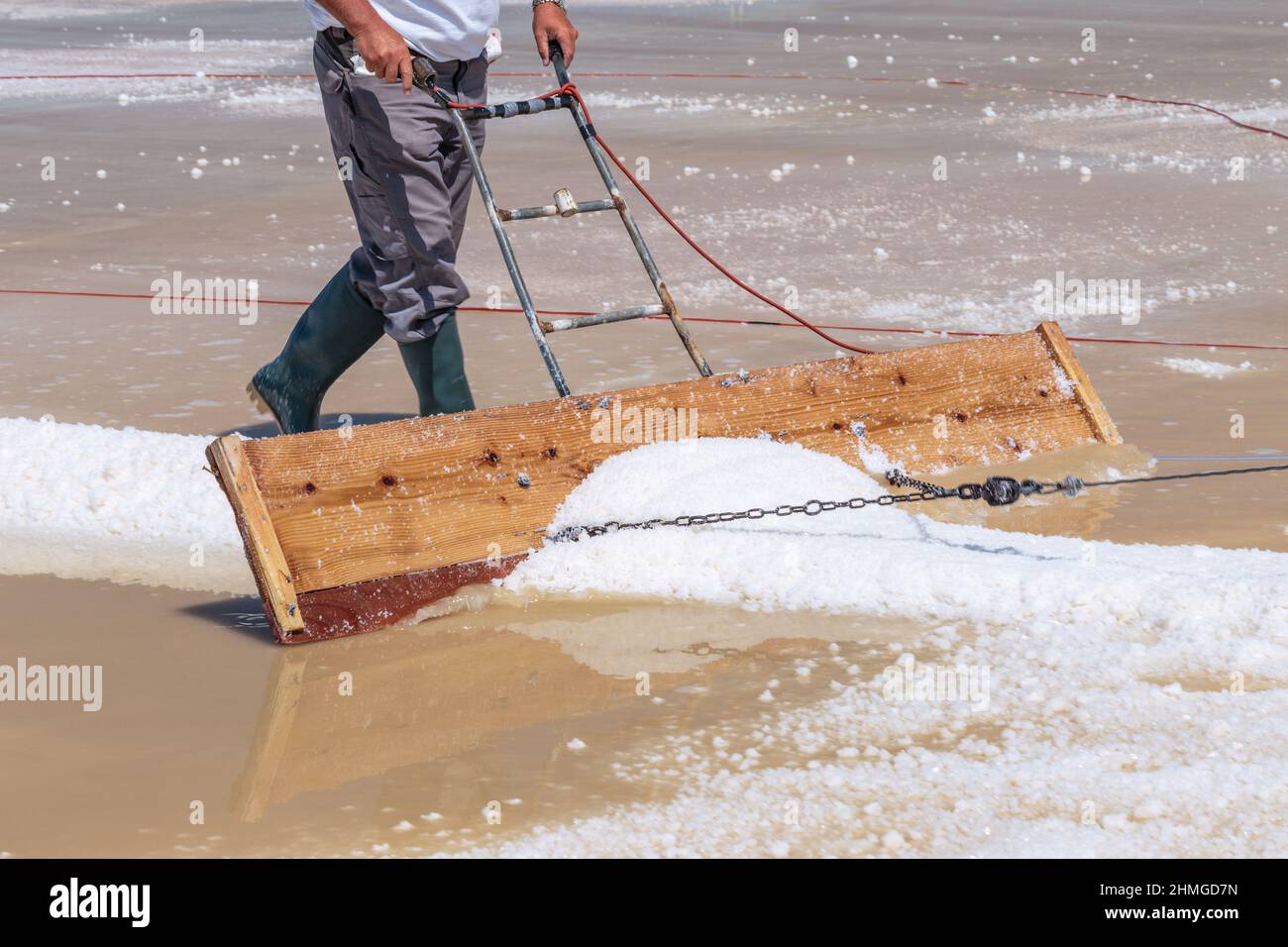 Man sums up the raw material in the sea salt factory Stock Photo - Alamy