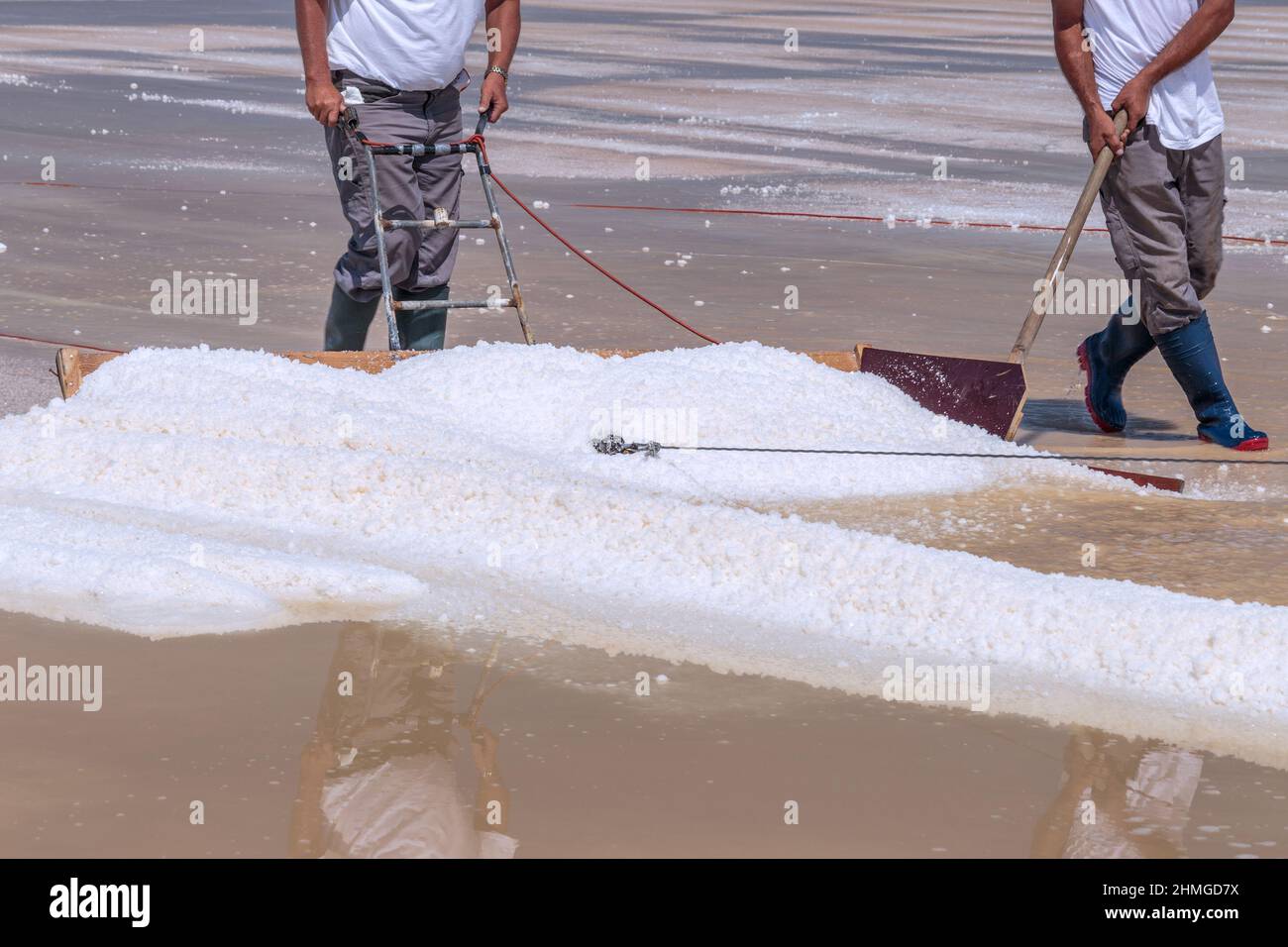Men sums up the raw material in the sea salt factory Stock Photo - Alamy