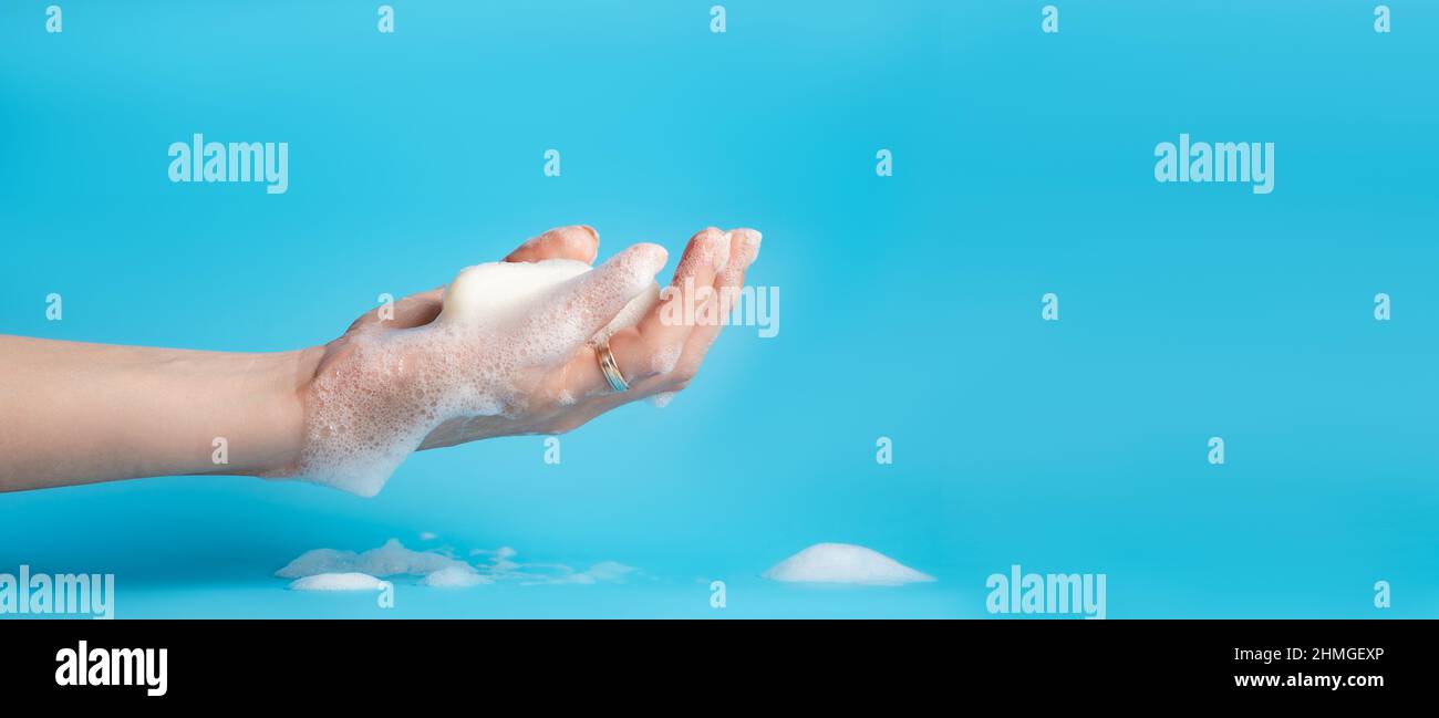 Global Handwashing Day. A bar of soap in a female hand on a blue ...