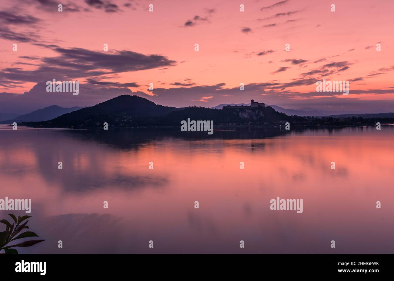 a pink sunrise overlooking the lake and medieval castle in Italy ...