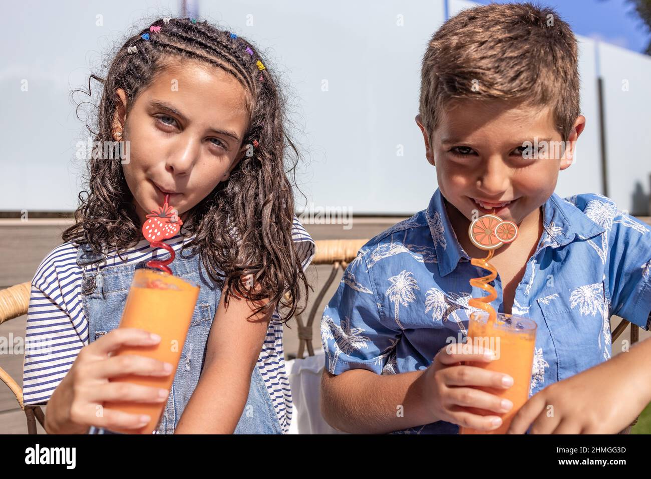 Two cute kids drinking orange juice outdoors Stock Photo - Alamy