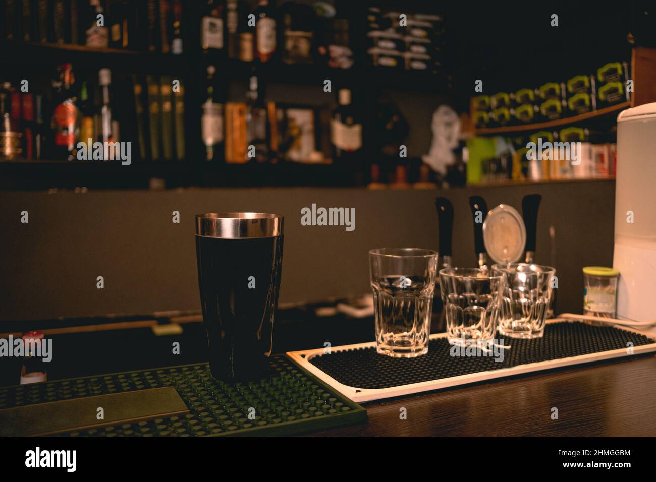 Empty glasses and cocktail shaker standing on bar counter Stock Photo ...