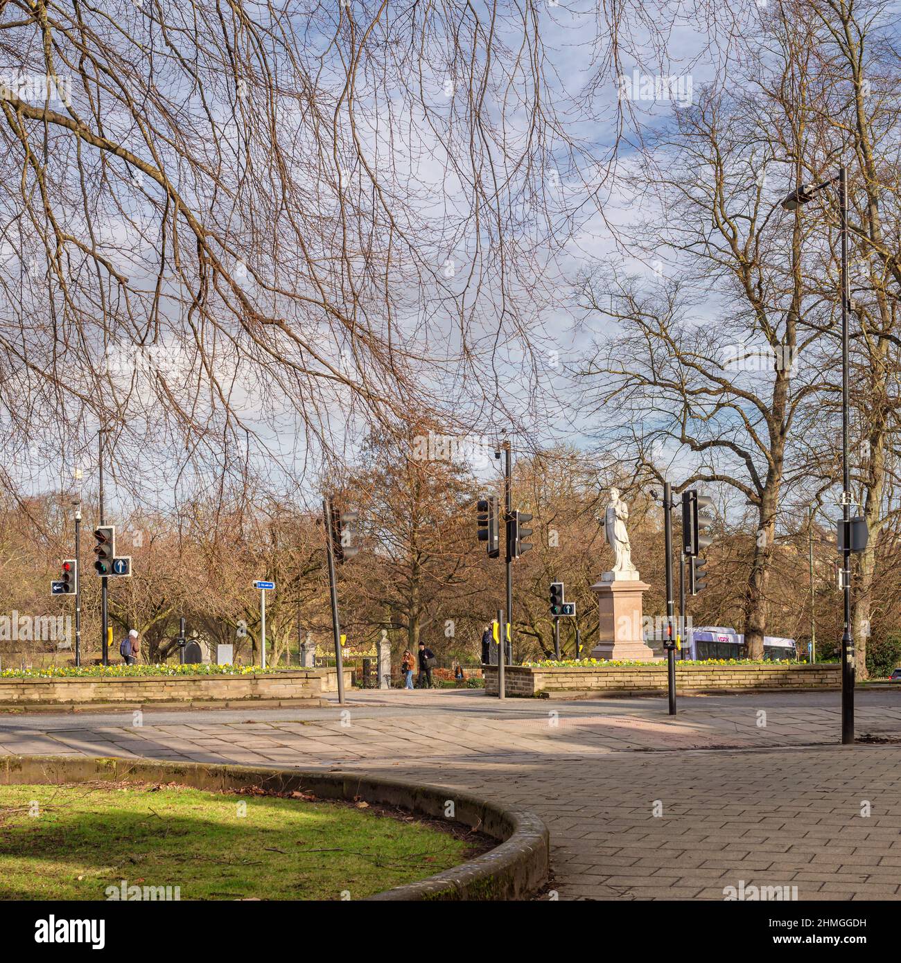 A statue stands at a road junction with traffic nearby. Traffic lights ...