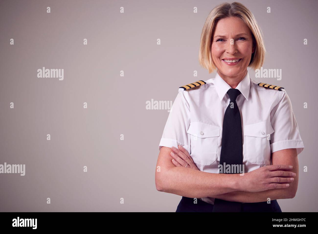 Studio Portrait Of Smiling Mature Female Airline Pilot Against Plain ...