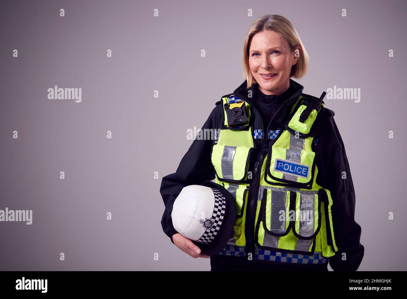 Studio Portrait Of Smiling Mature Female Police Officer Holding Hat ...