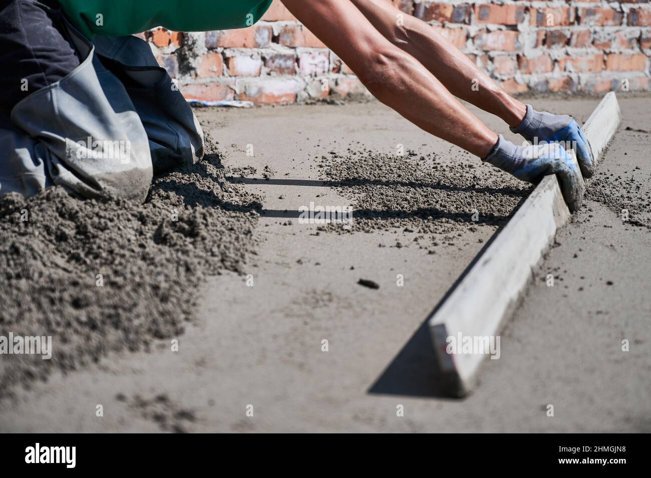 Close up of man builder placing screed rail on the floor covered with ...