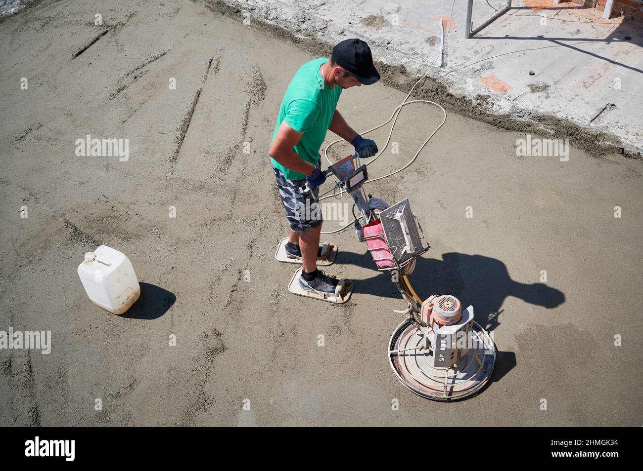Top view of man builder using troweling machine while screeding floor ...