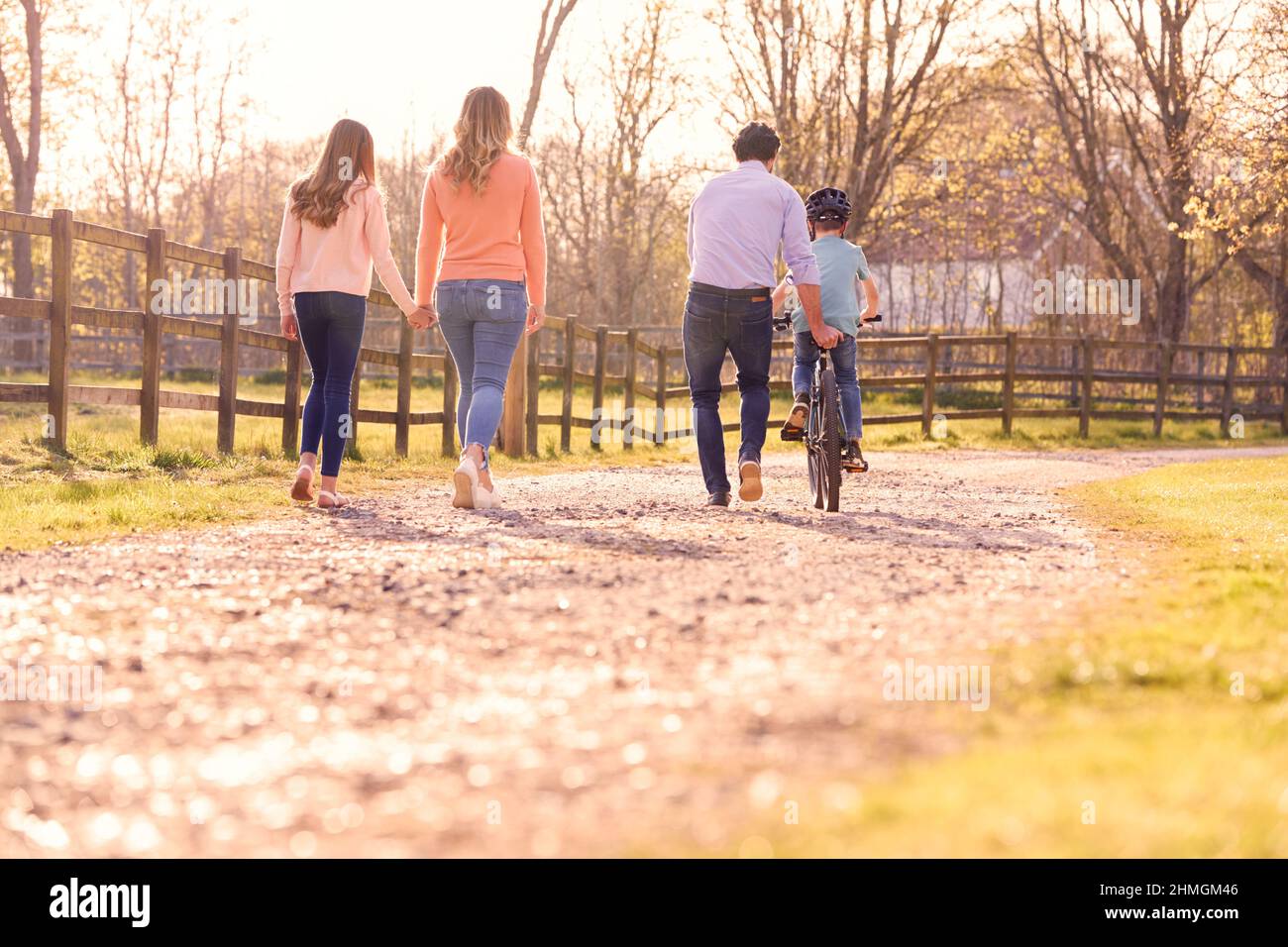 Rear View Of Family On Summer Walk In Countryside Teaching Son To Ride ...