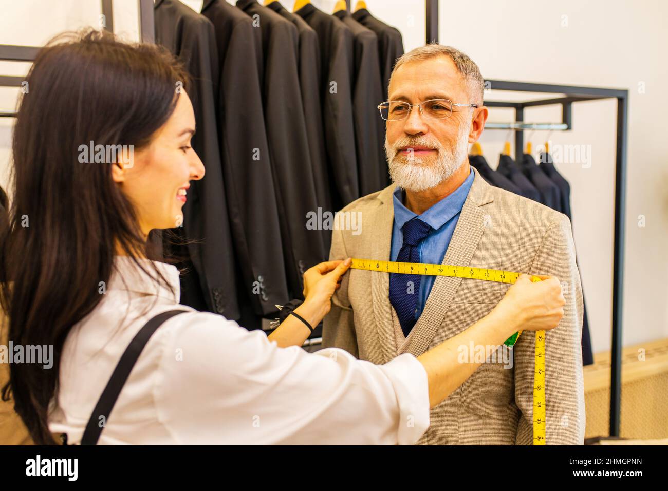 a professional tailor woman trying on a tailor-made suit for an elderly ...