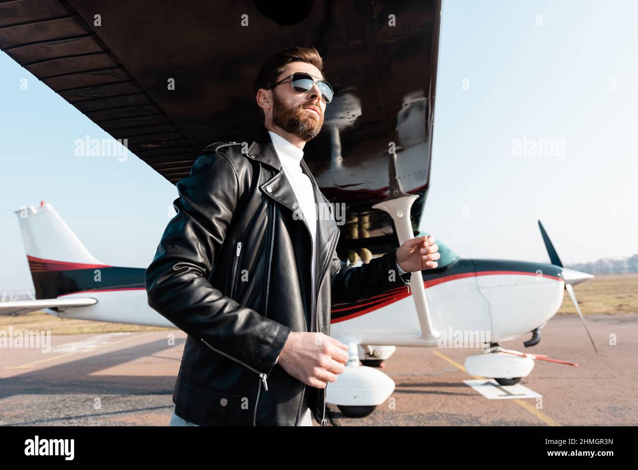 low angle view of bearded pilot in sunglasses and leather jacket ...