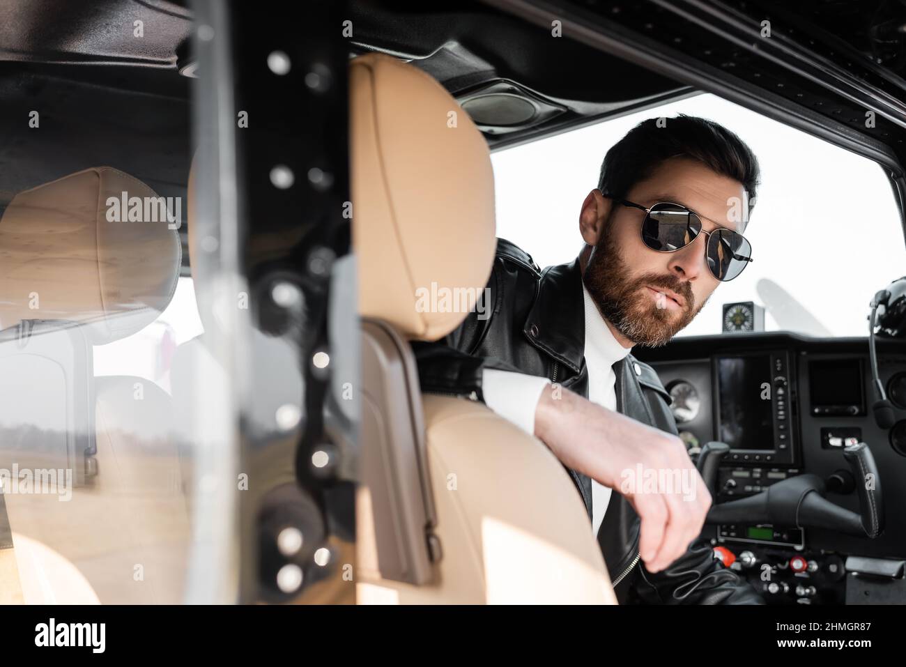 bearded pilot in stylish sunglasses and leather jacket sitting in ...