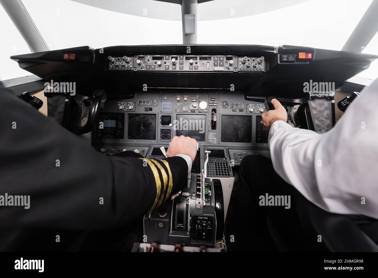 cropped view of pilots using yoke and thrust lever in airplane ...