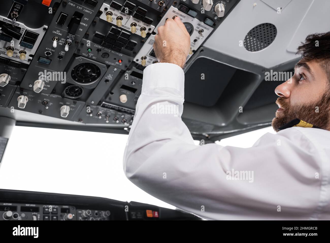 bearded pilot pressing button on overhead panel in airplane simulator ...