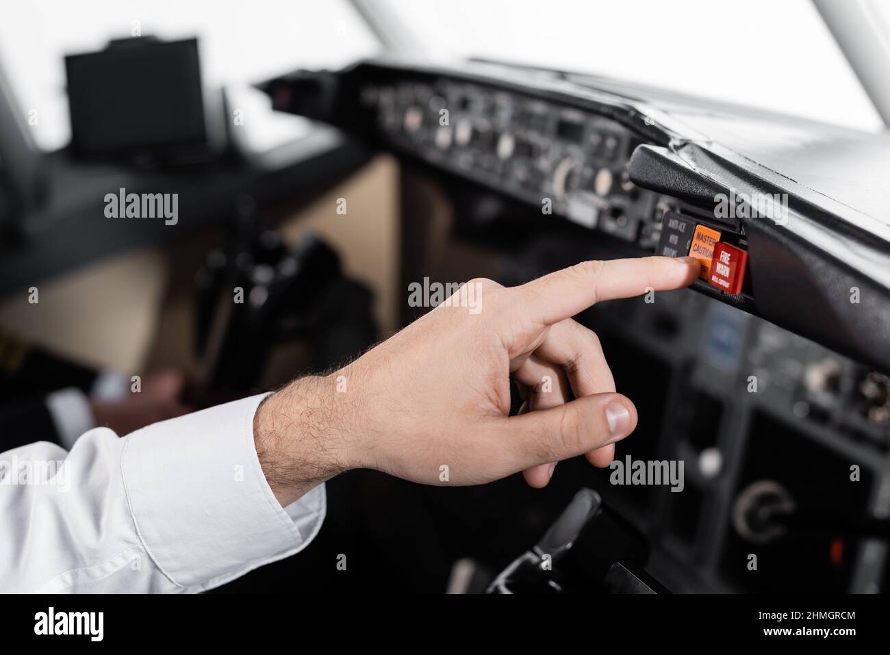 cropped view of pilot pressing master caution button in airplane ...