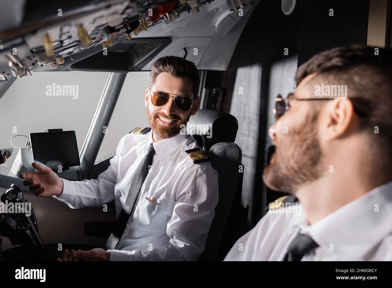 cheerful pilots in sunglasses looking at each other in airplane Stock ...
