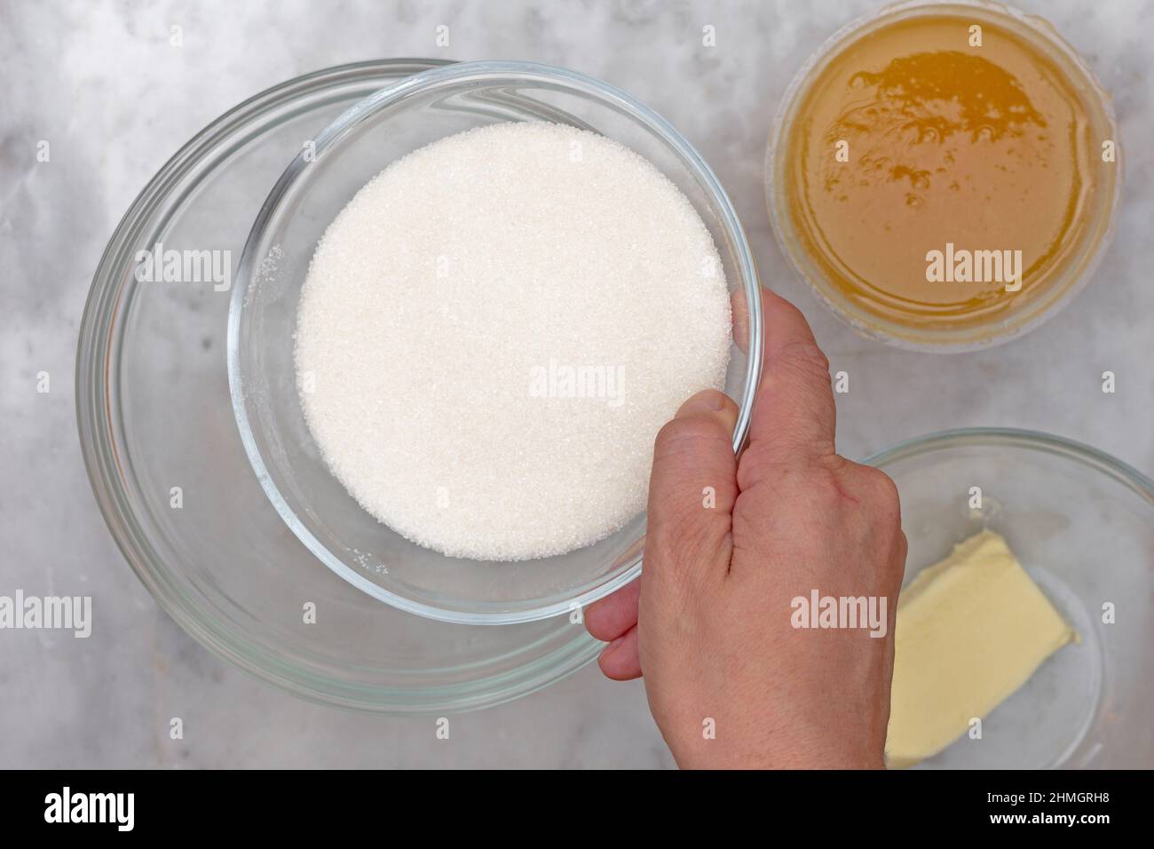 Top view of woman hand putting sugar into glass bowl as ingredient of ...