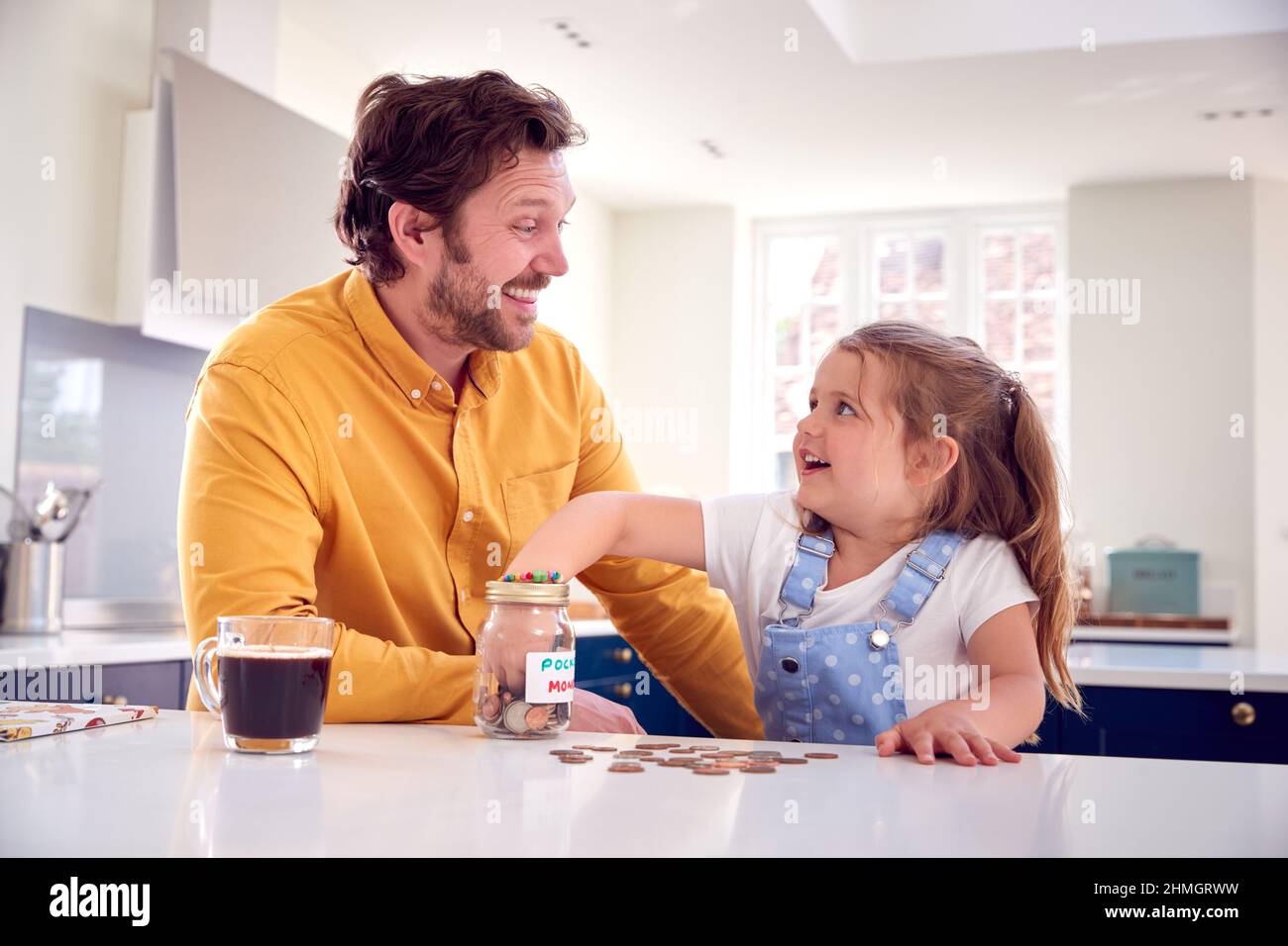 Father And Daughter Counting Pocket Money In Jar On Kitchen Counter ...