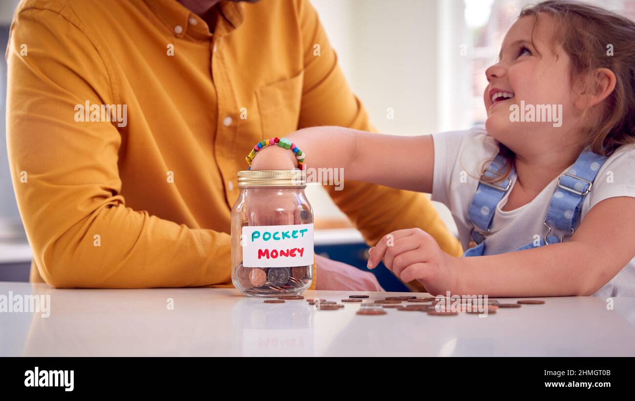 Close Up Of Father And Daughter Counting Pocket Money In Jar On Kitchen ...
