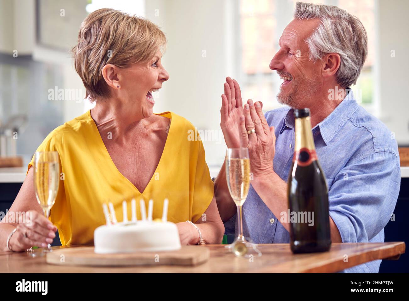 Retired Couple Celebrating Birthday With Glass Of Champagne And Cake At ...