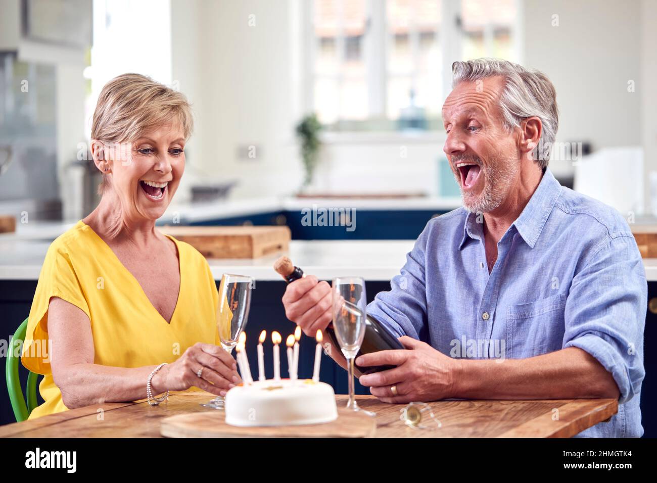 Retired Couple Celebrating Birthday With Glass Of Champagne And Cake At ...