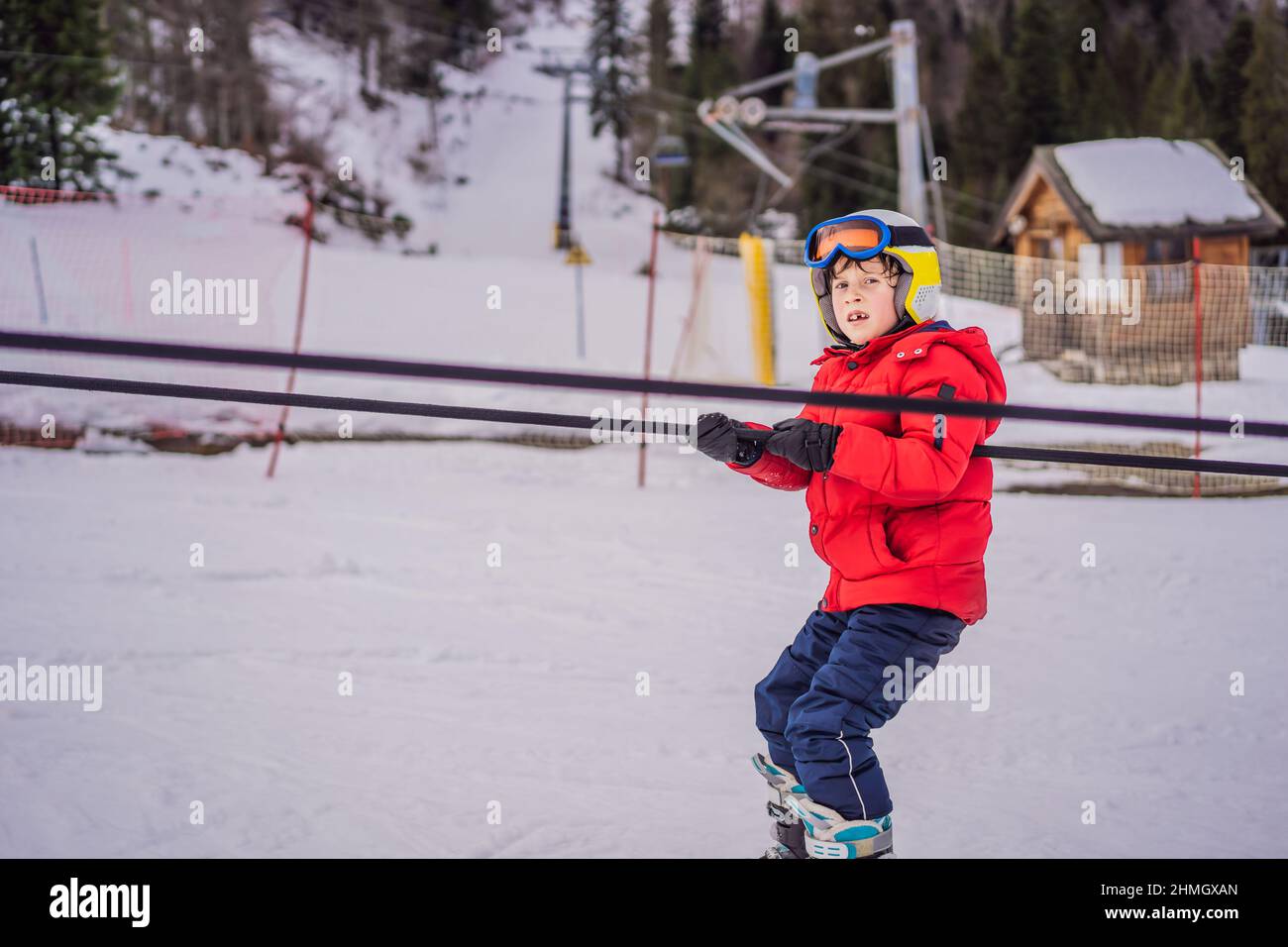 Boy uses a training lift. Child skiing in mountains. Active toddler kid ...