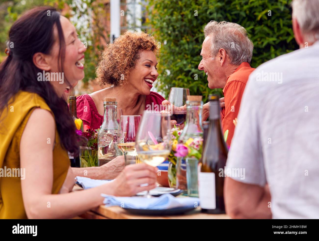 Group Of Mature Friends Talking Around Table At Summer Dinner Party In ...