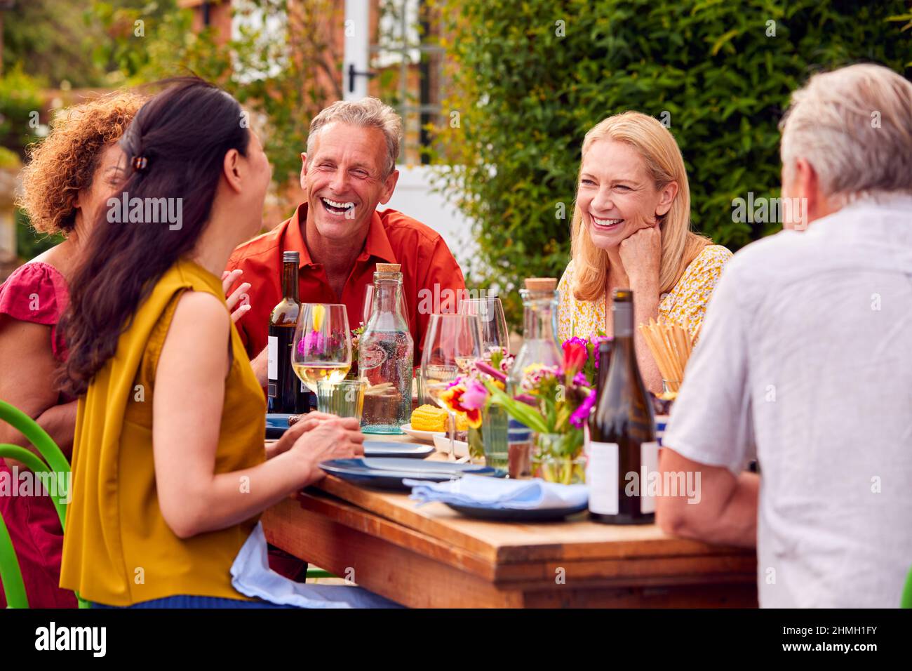 Group Of Mature Friends Talking Around Table At Summer Dinner Party In ...