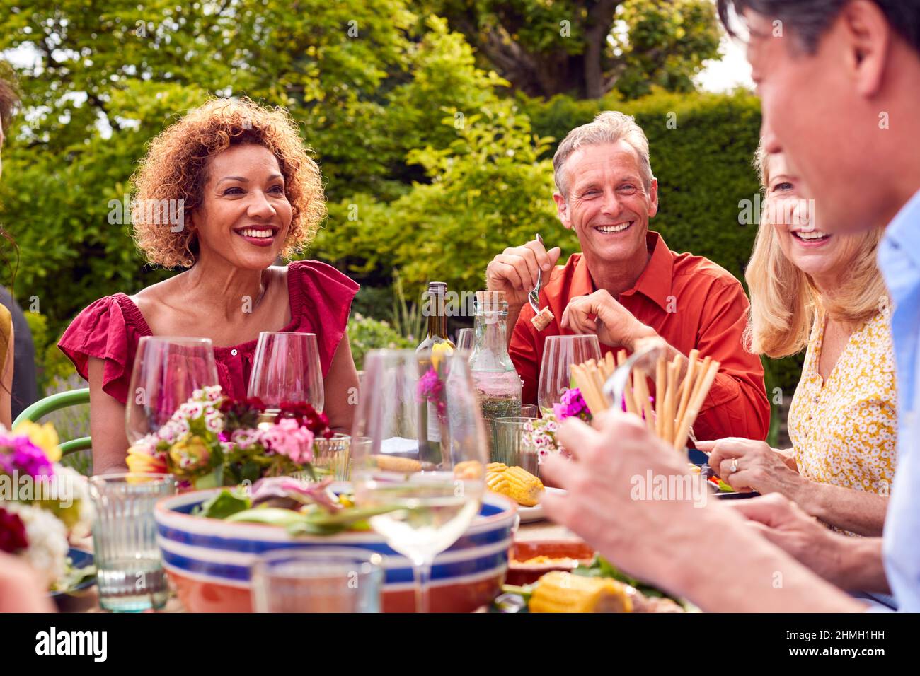 Group Of Mature Friends Talking Around Table At Summer Dinner Party In ...