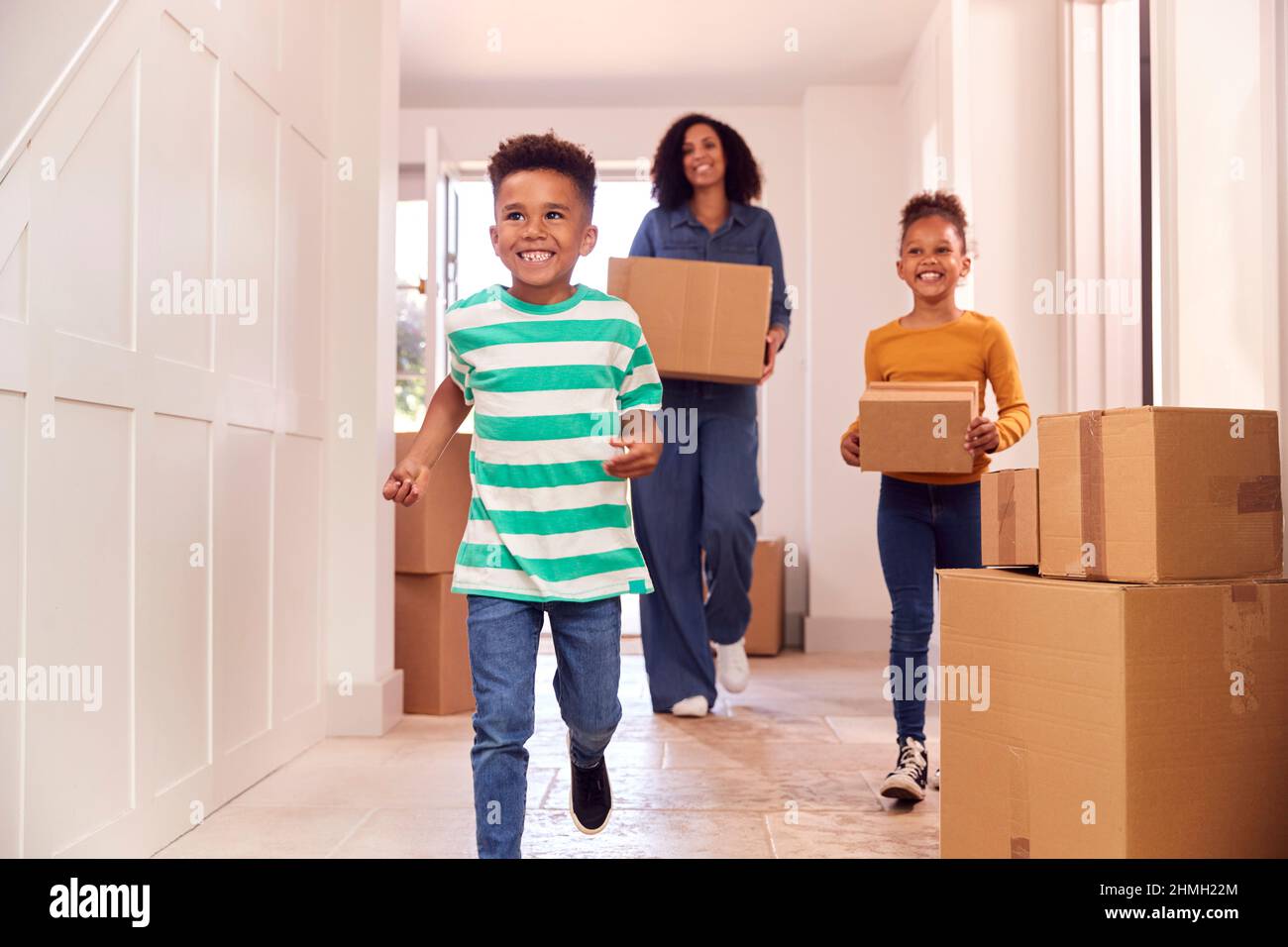 Children Helping Mother To Carry Boxes Into New Home On Moving In Day ...