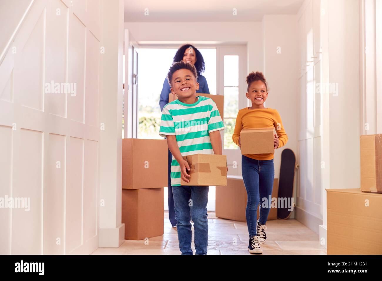 Children Helping Mother To Carry Boxes Into New Home On Moving In Day ...