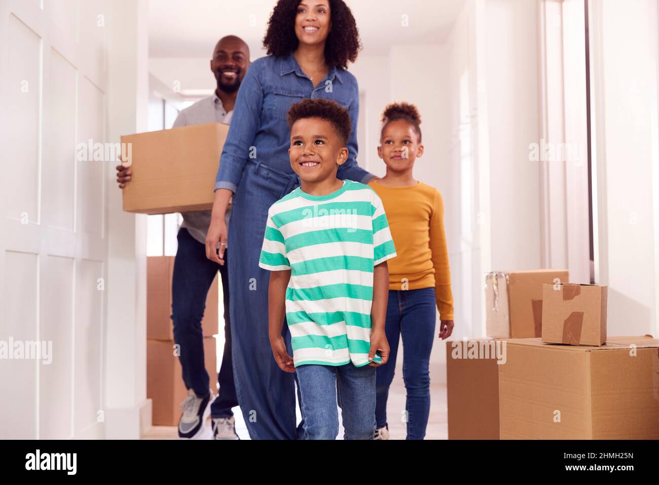 Children Helping Parents To Carry Boxes Into New Home On Moving In Day ...
