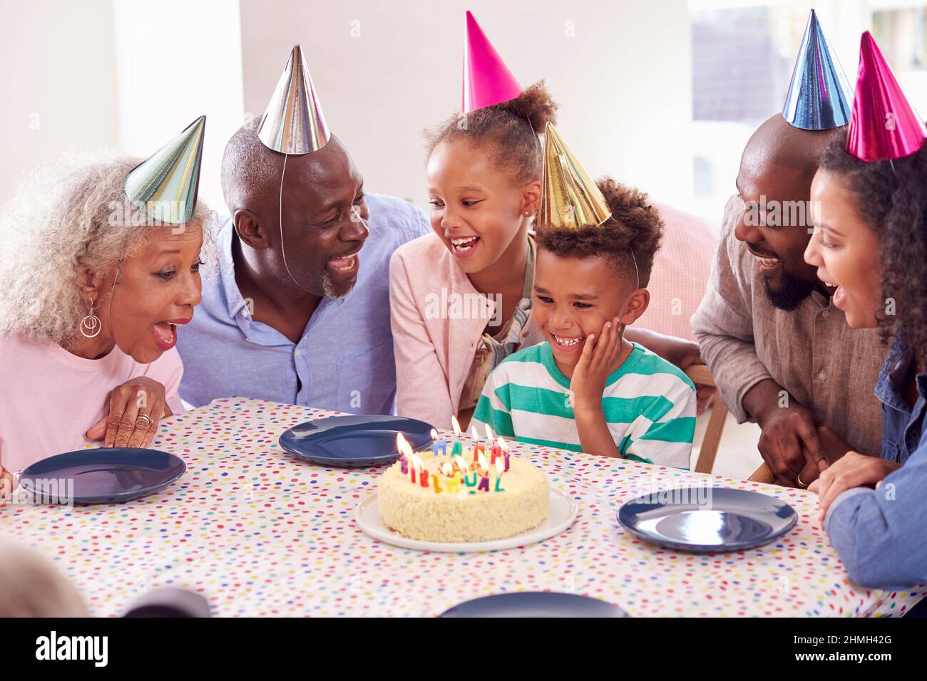 Multi Generation Family Sitting Around Table At Home Celebrating Boy's ...