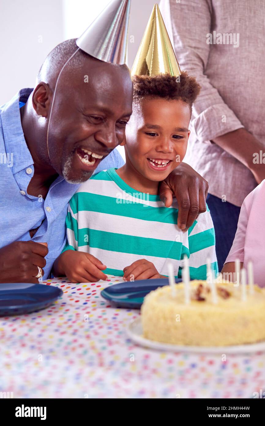 Multi Generation Family Sitting Around Table At Home Celebrating Boy's ...