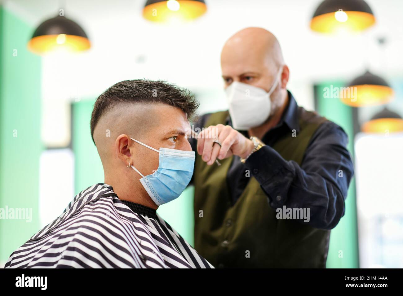Professional barber wearing a mask during the Covid-19 pandemic cutting ...