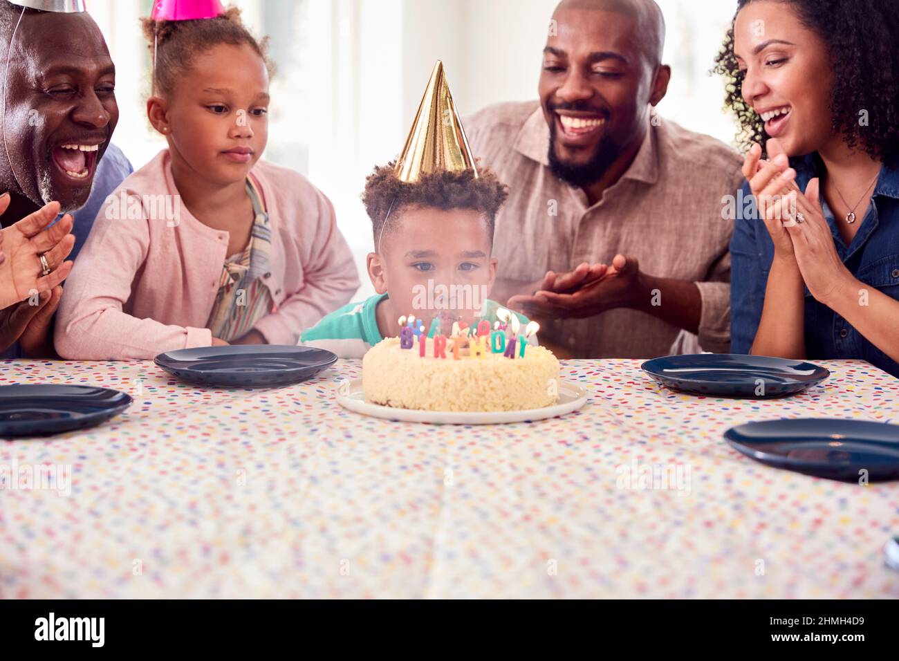 Multi Generation Family Sitting Around Table At Home Celebrating Boy's ...