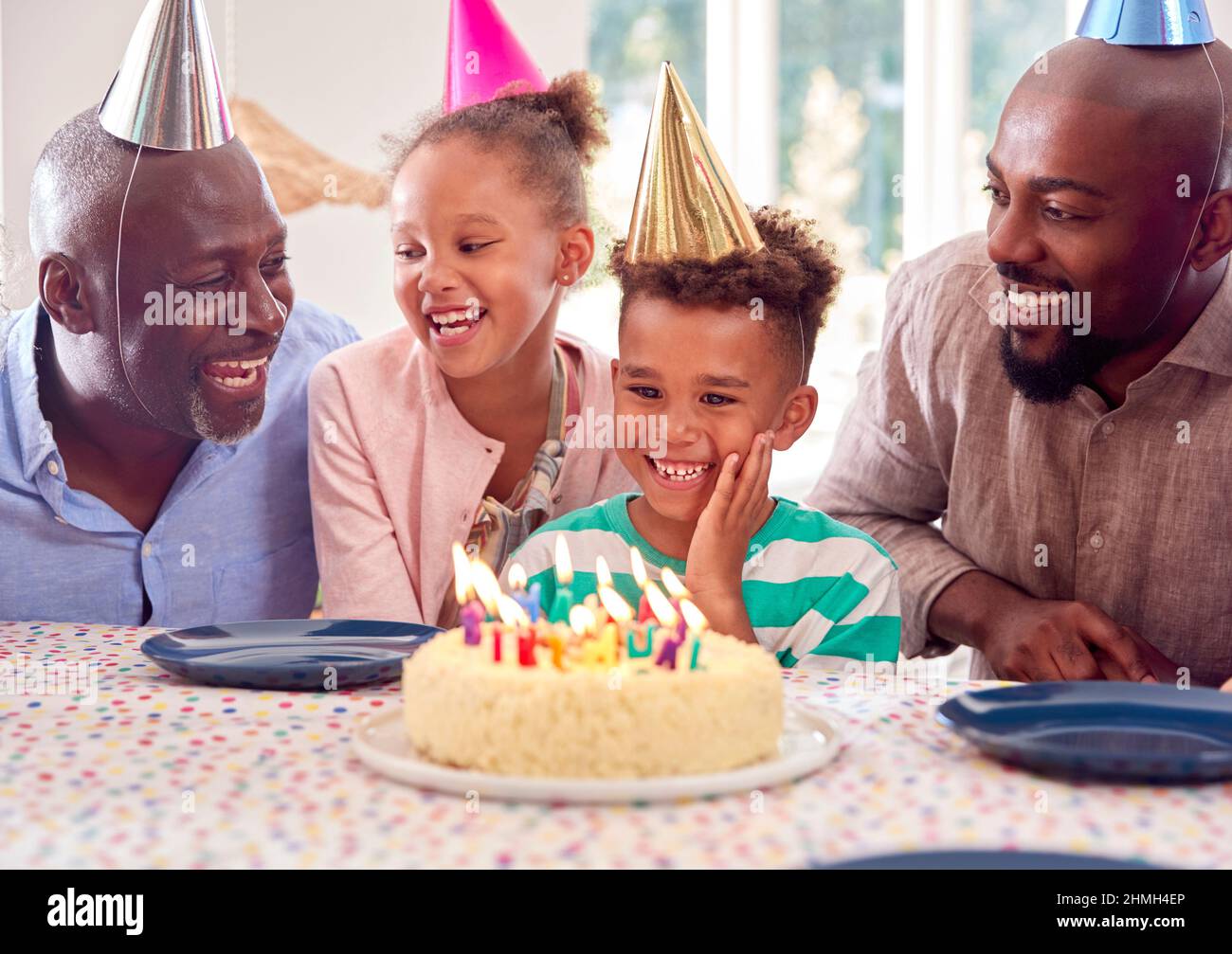 Multi Generation Family Sitting Around Table At Home Celebrating Boy's ...