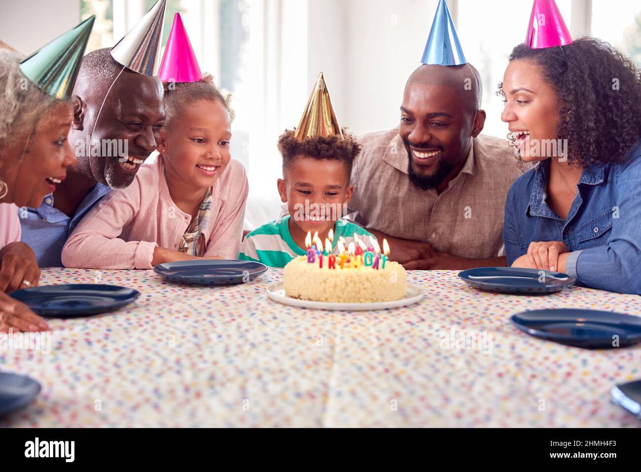 Multi Generation Family Sitting Around Table At Home Celebrating Boy's ...