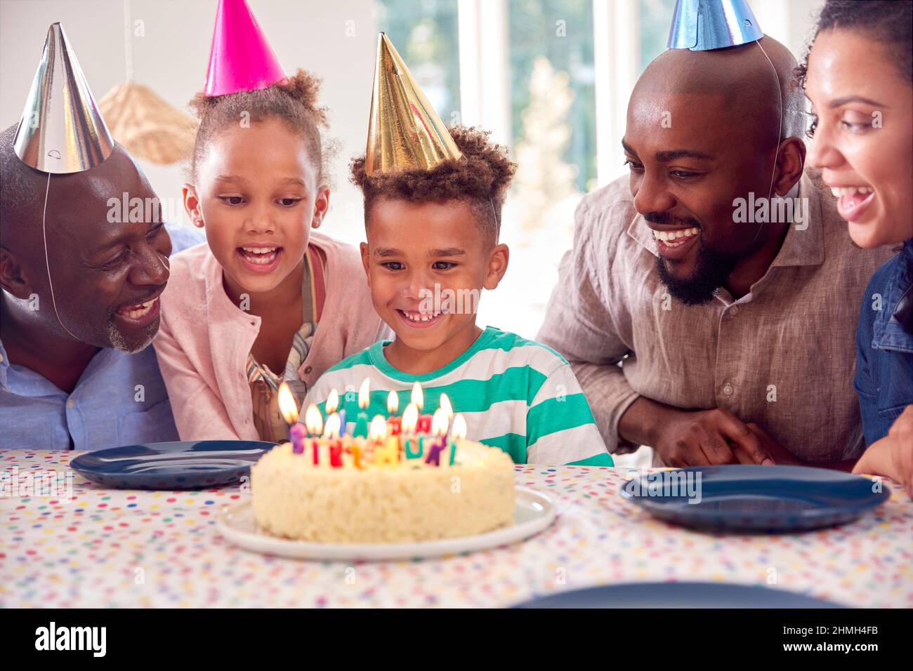 Multi Generation Family Sitting Around Table At Home Celebrating Boy's ...
