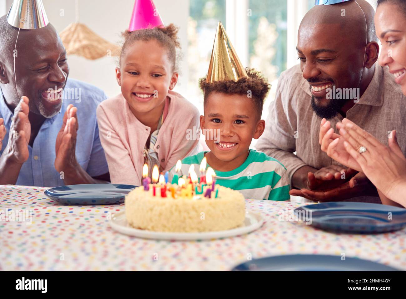 Multi Generation Family Sitting Around Table At Home Celebrating Boy's ...