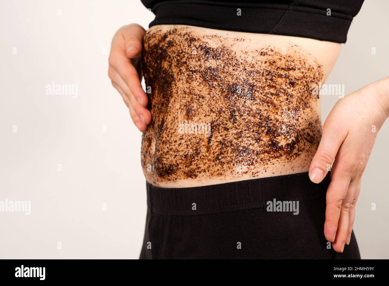 A woman applies a coffee scrub to the abdomen, anti-cellulite massage ...