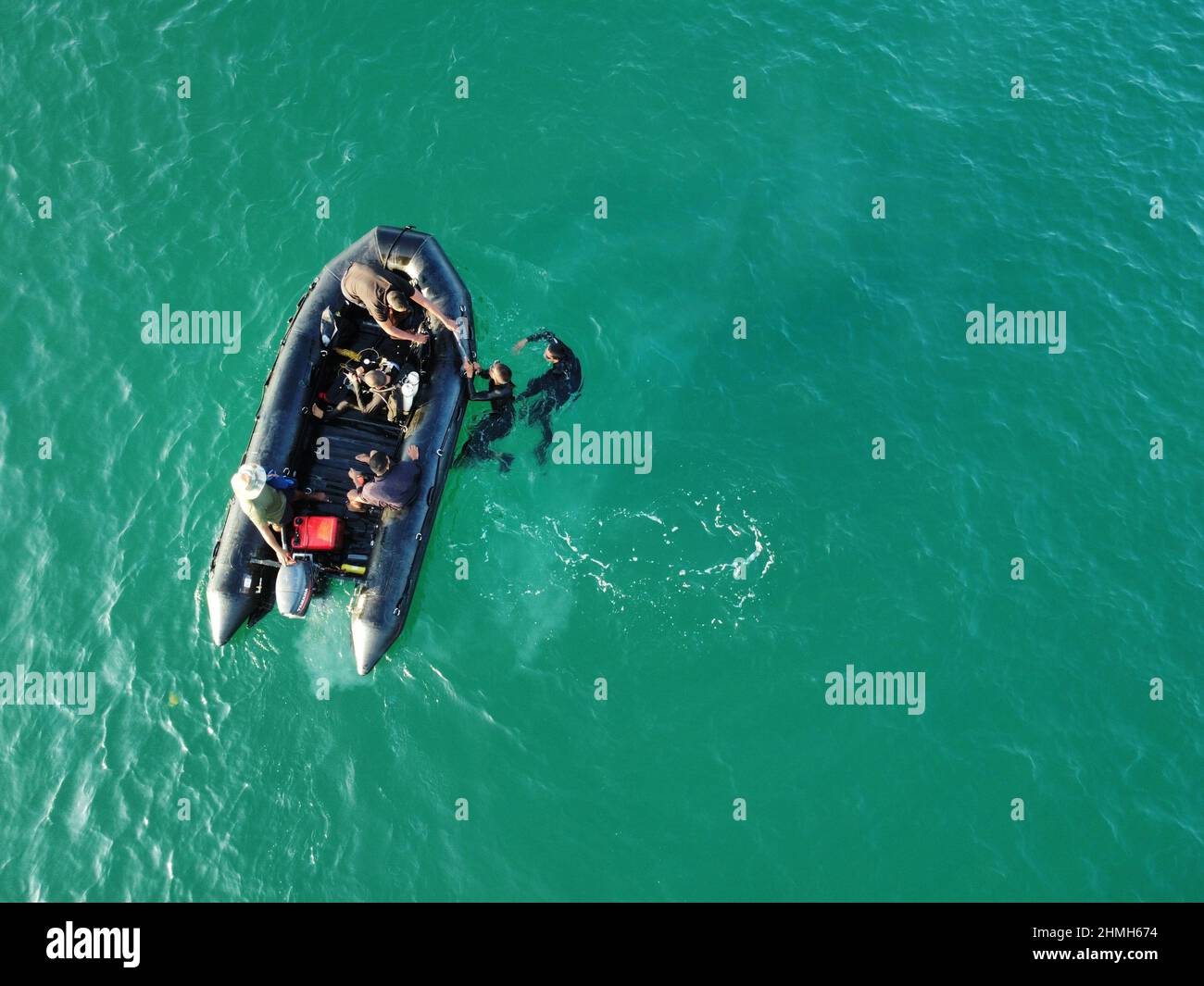 Aerial view of the male on the boat helping the divers to get out of ...