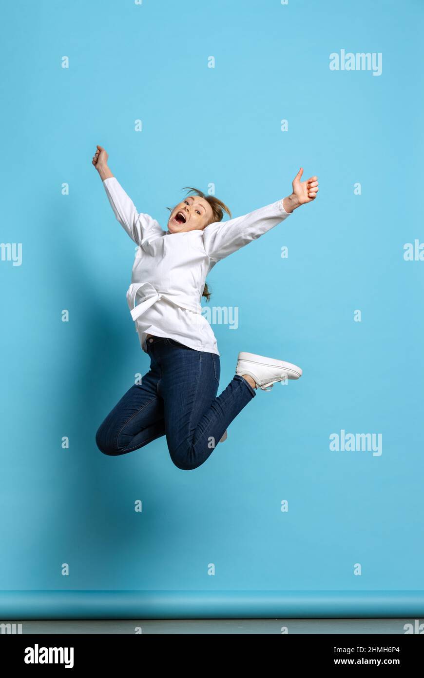 Full-length portrait of excited young girl jumping isolated on blue ...