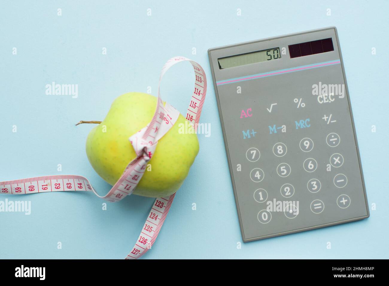 Calculator and apple with measuring tape on blue background. Weight ...