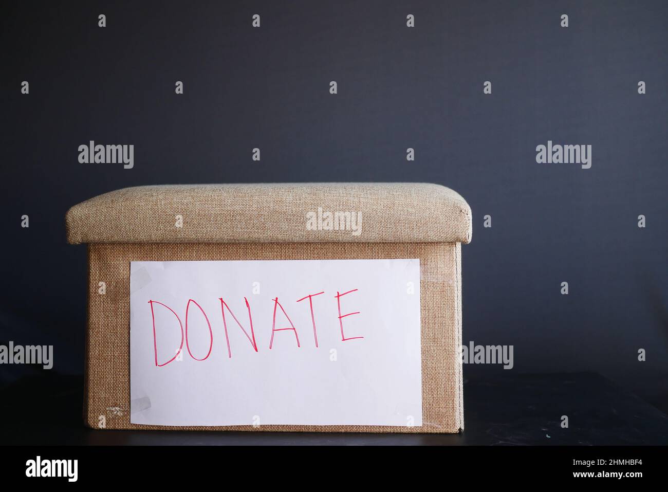 Donation box on table against black background Stock Photo - Alamy