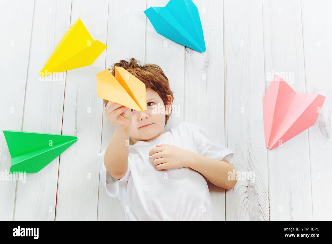 Happy laughing child throwing paper airplane indoors. Happy childhood ...