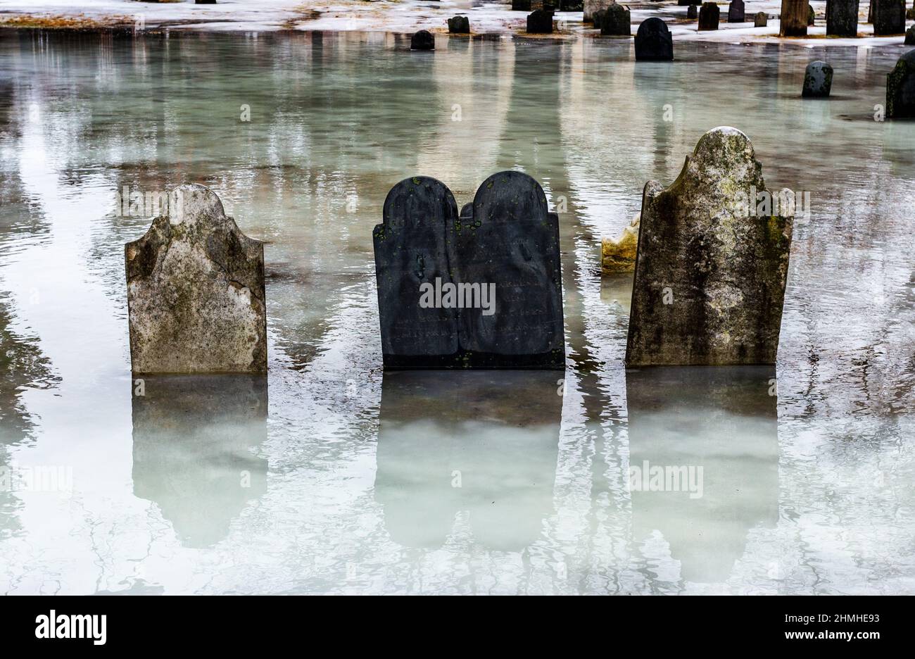 Three old tombstones in a flooded and frozen colonial era Massachusetts ...
