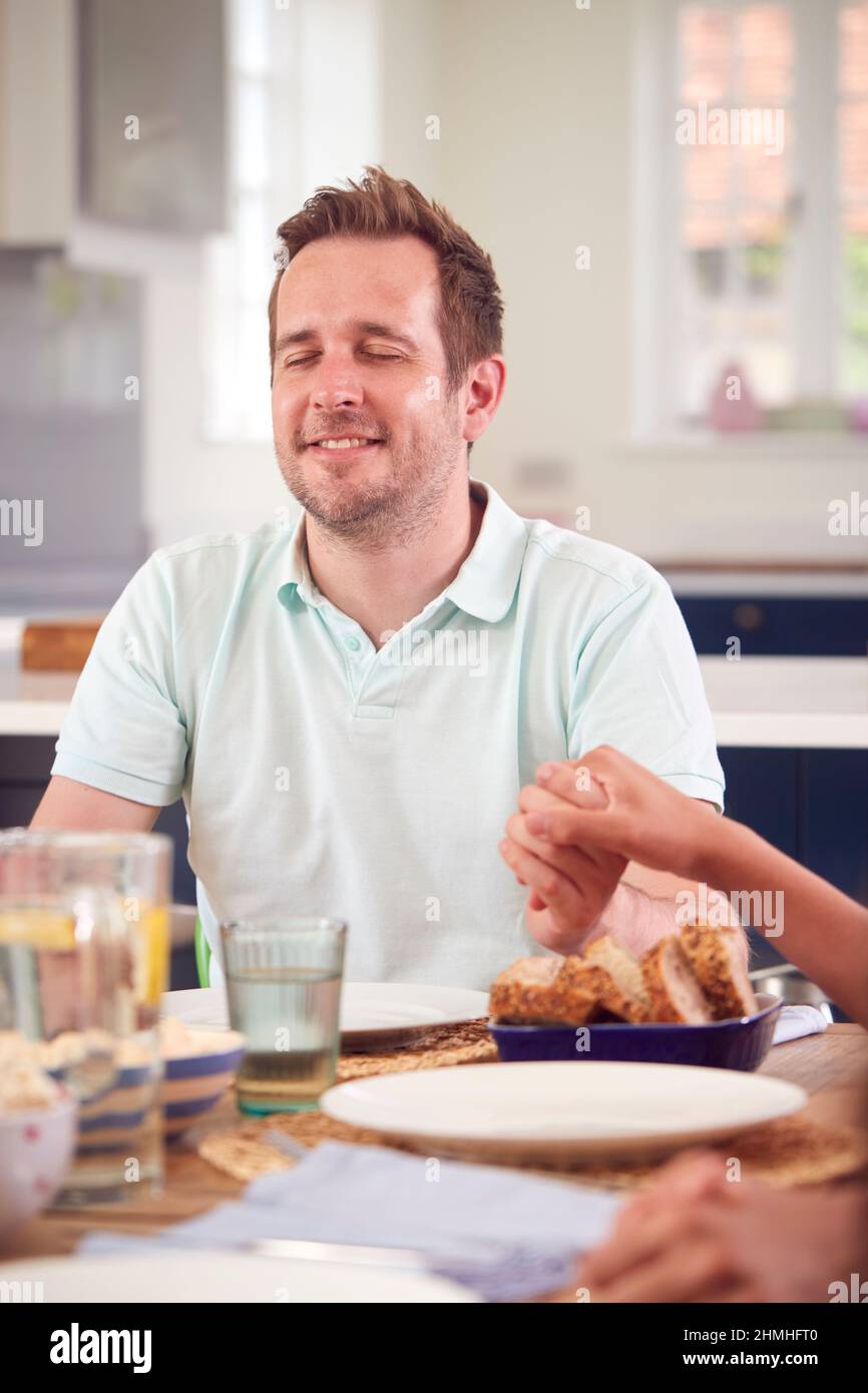 Family Holding Hands Around Table At Home Saying Grace Before Eating ...