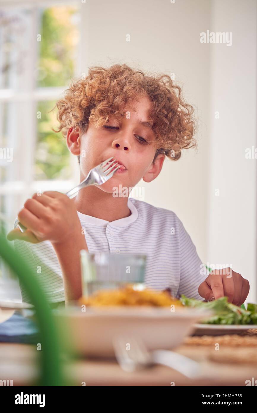 Boy Sitting Around Table At Home With Family Eating Meal Together Stock ...