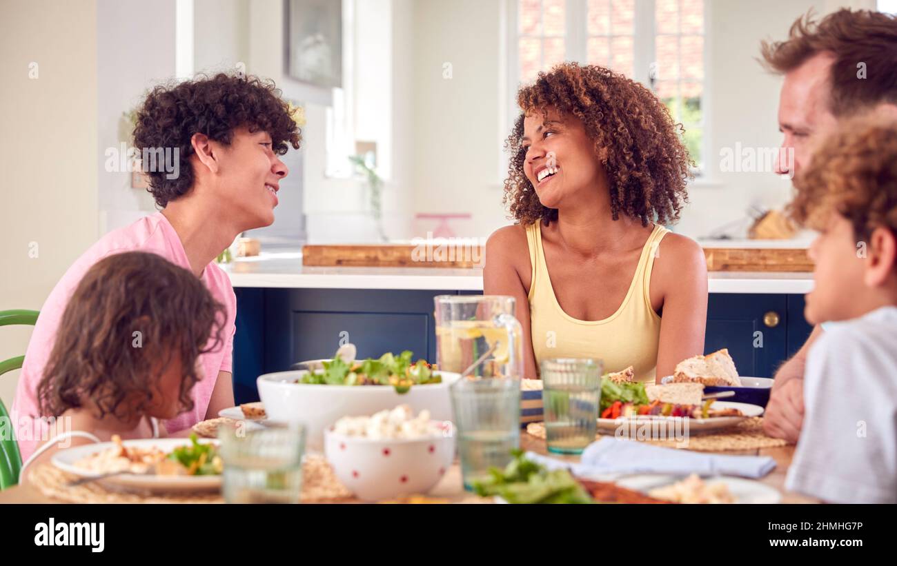Family Sitting Around Table At Home Eating Meal Together Stock Photo ...